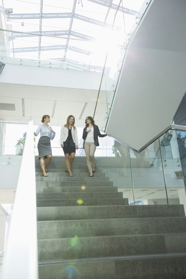 Happy Businesswomen Conversing while Moving Down Steps in Office Stock ...