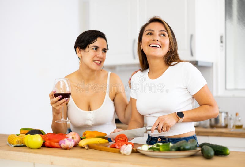 Happy Young Lesbian Couple Drinking Wine And Cooking Dinner In Kitchen