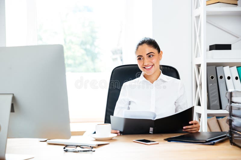 Happy Charming Businesswoman Holding Documents and Looking at Computer ...