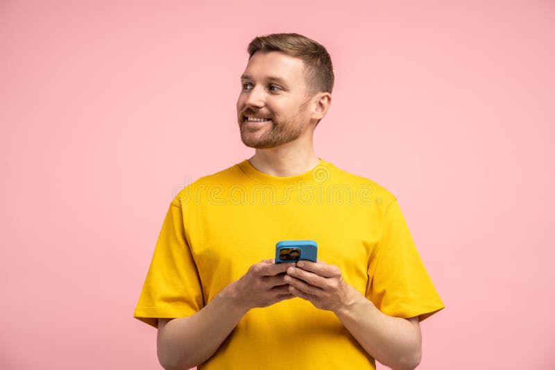Happy Cheerful Guy Holding Smartphone Interested Looking Away Standing ...