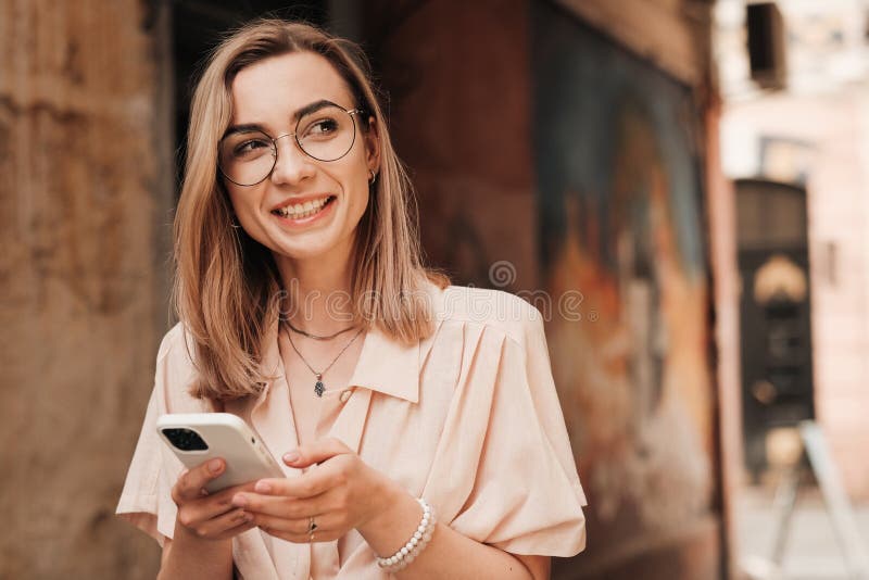 Happy Cheerful Young Woman With Eyeglasses Texting On Smartphone While