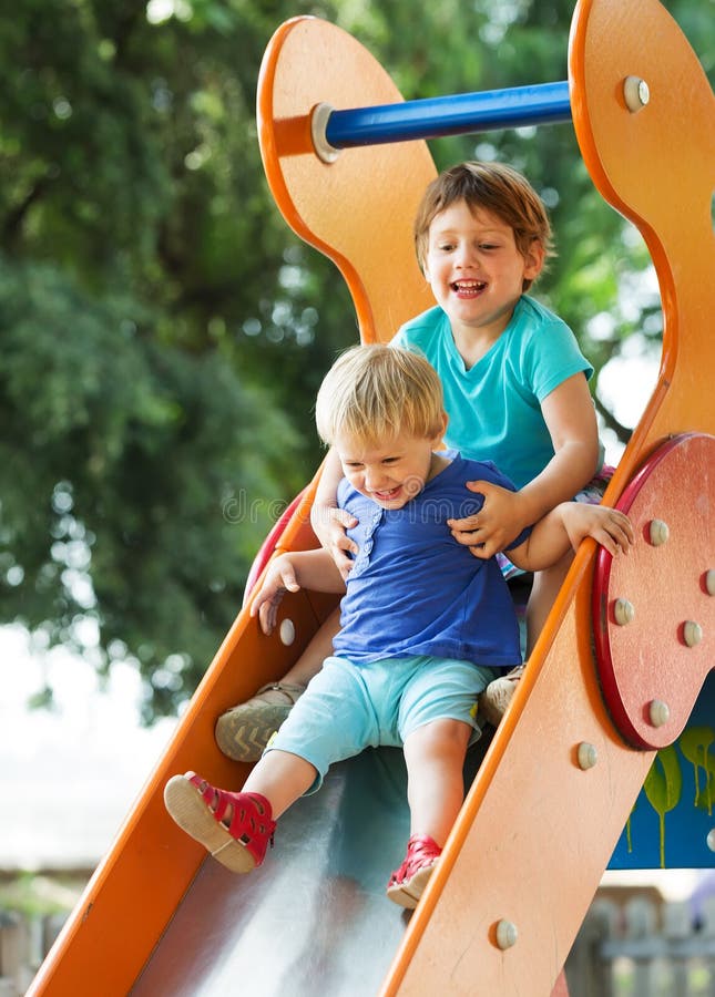 Two Happy Children on Slide at Playground Stock Image - Image of family ...