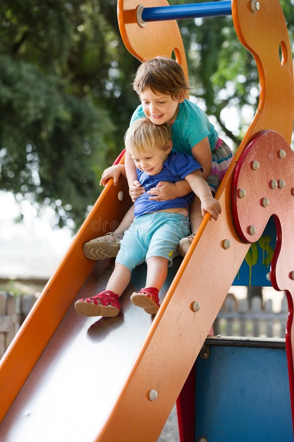Two Happy Children on Slide at Playground Stock Image - Image of family ...