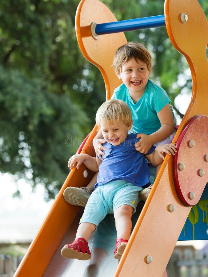 Two Happy Children on Slide at Playground Stock Image - Image of family ...