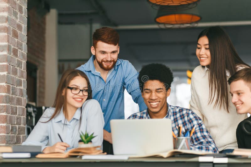 Happy Classmates Discussing Project at Library, Using Laptop Stock ...
