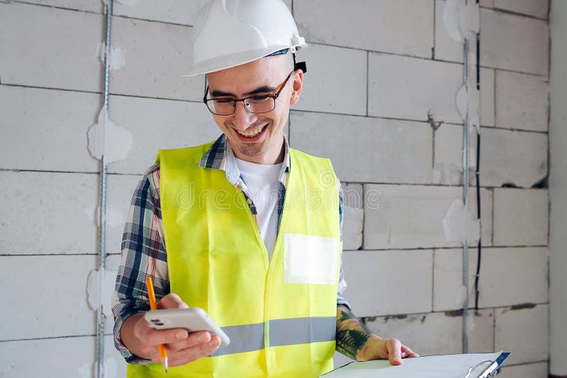 Happy Construction Engineer Looking at His Phone, Scrolling Stock Photo ...
