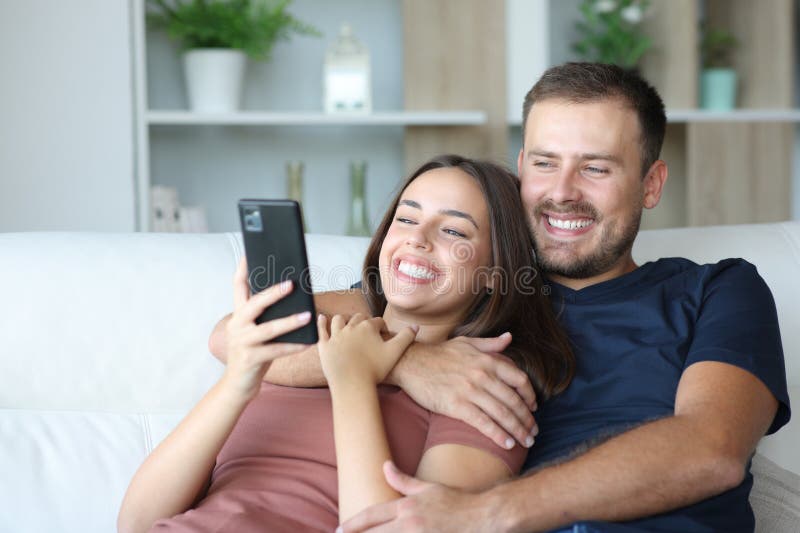 Happy Couple Checking Phone and Laughing at Home Stock Photo - Image of ...