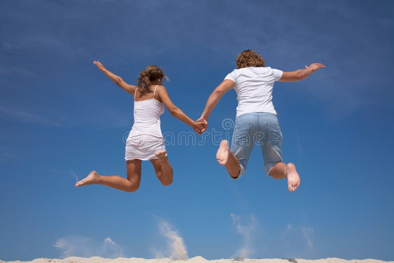 Couple Jumping Off Sand Dune Stock Photo - Image of smiling, blue: 2542314
