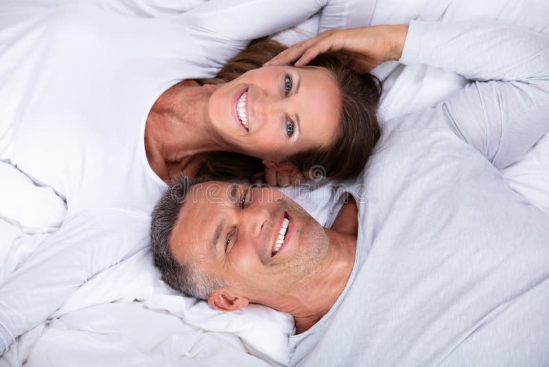 Happy Couple Lying on Bed stock photo. Image of female - 181813482