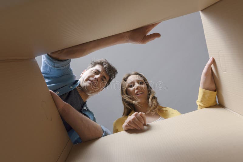 Happy Couple Opening a Cardboard Box and Looking Inside Stock Photo ...