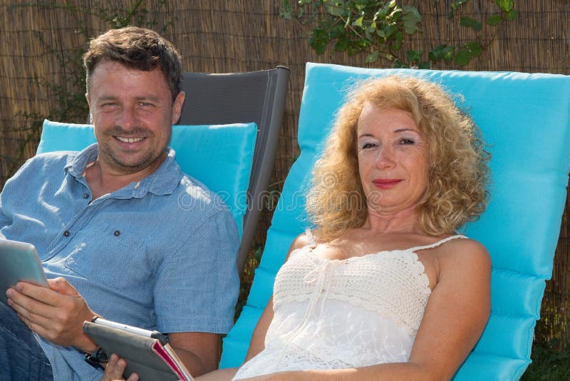 Happy Couple Resting in Deck Chairs by Pool with Tablet Stock Image ...