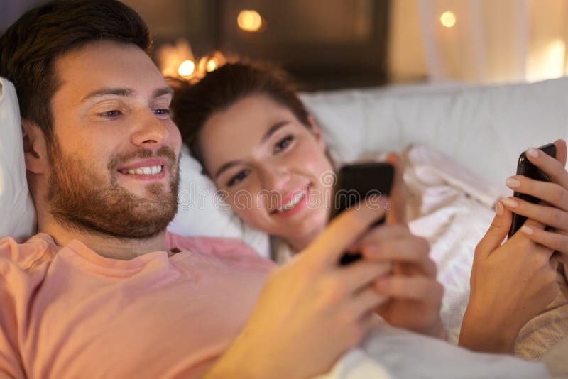 Happy Couple Using Smartphones in Bed at Night Stock Photo - Image of ...