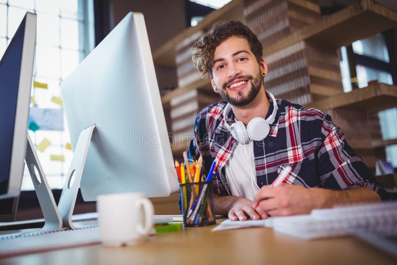 Happy Creative Businessman Writing in Book at Computer Desk Stock Photo ...