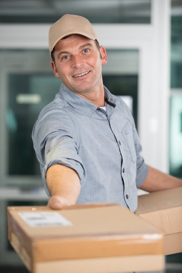 Happy Delivery Man Giving Parcel To Camera Stock Photo - Image of ...