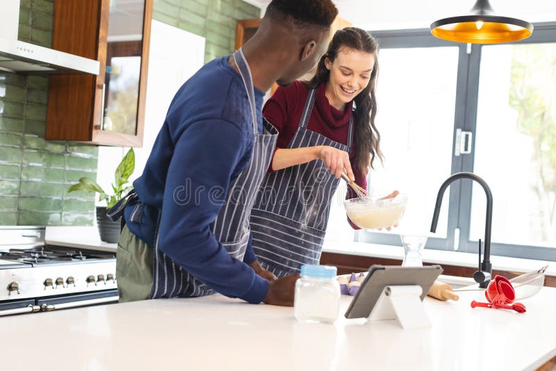 Happy Diverse Couple Baking Together in Kitchen, Using Tablet at Home ...