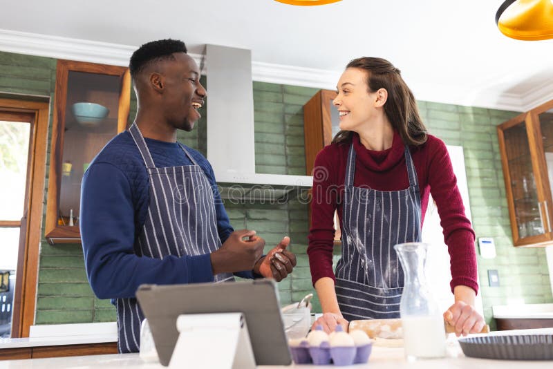 Happy Diverse Couple Baking Together in Kitchen, Using Tablet at Home ...