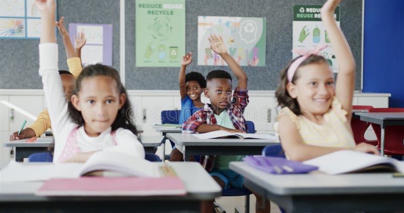 Happy Diverse Schoolchildren at Desks Raising Hands in Classroom at ...