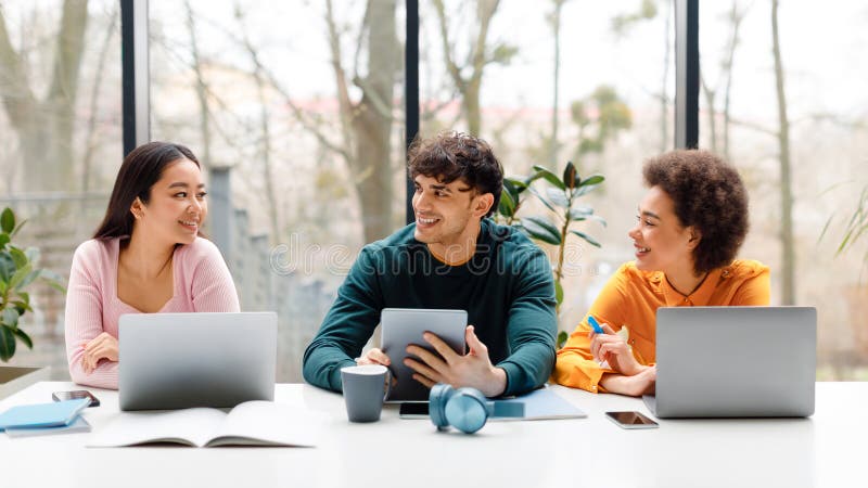Happy Diverse Three Students Using Various Gadgets and Chatting ...