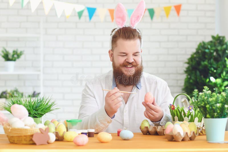 Happy Easter.a Funny Fat Man Decorates Eggs while Sitting at a Table ...