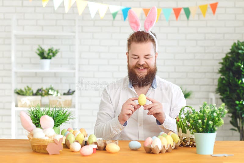 Happy Easter.a Funny Fat Man Decorates Eggs while Sitting at a Table ...