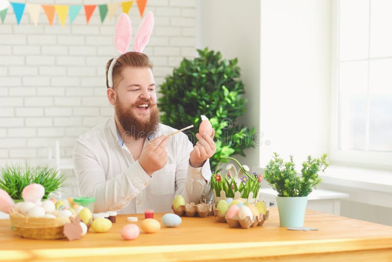 Happy Easter.a Funny Fat Man Decorates Eggs while Sitting at a Table ...