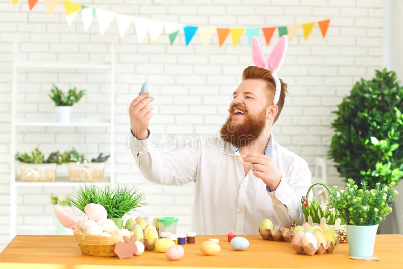 Happy Easter.a Funny Fat Man Decorates Eggs while Sitting at a Table ...