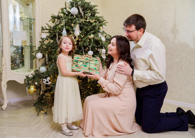 Happy Family with Box of Gift by Christmas Tree. Tradition Giving Gifts ... Happy Family with Box of Gift by Christmas Tree. Tradition Giving Gifts ...