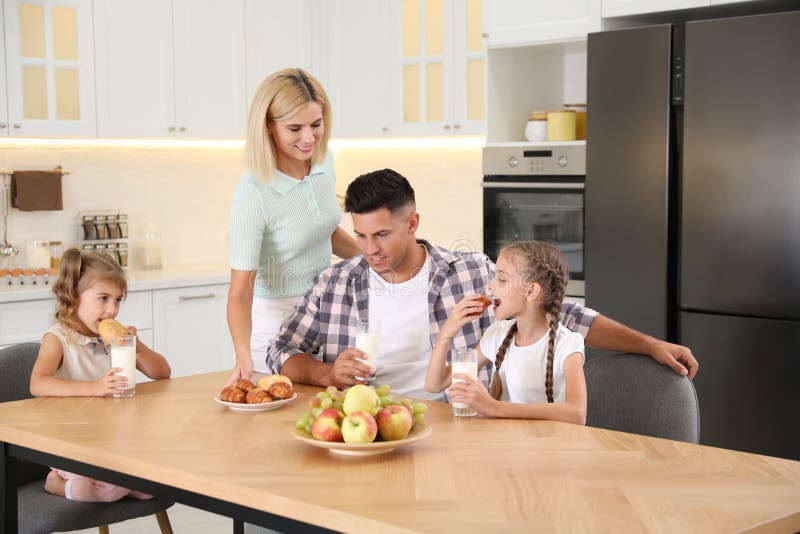 Happy Family Eating Together at Table in Modern Kitchen Stock Photo ...