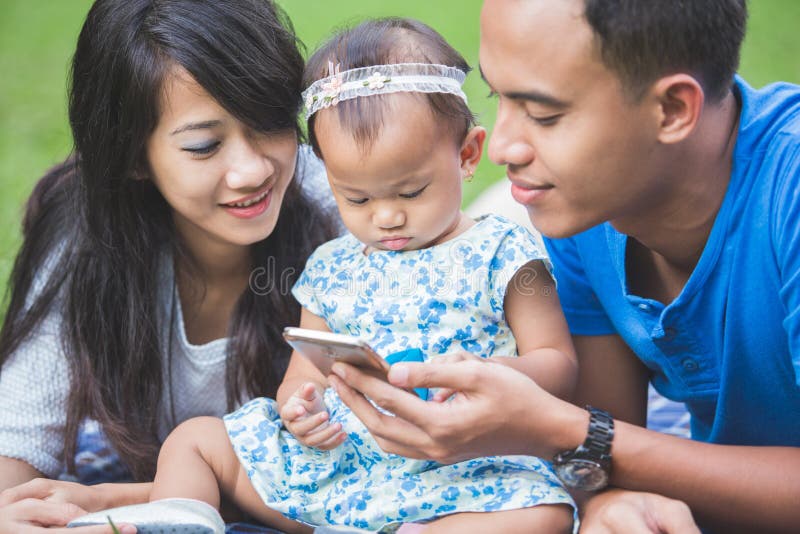 Happy Family Lying in the Grass Using Smart Phone Stock Photo - Image ...
