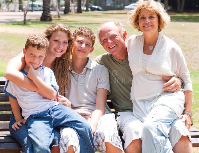 Happy Family Sitting on Park Bench Stock Photo - Image of bench, casual ...