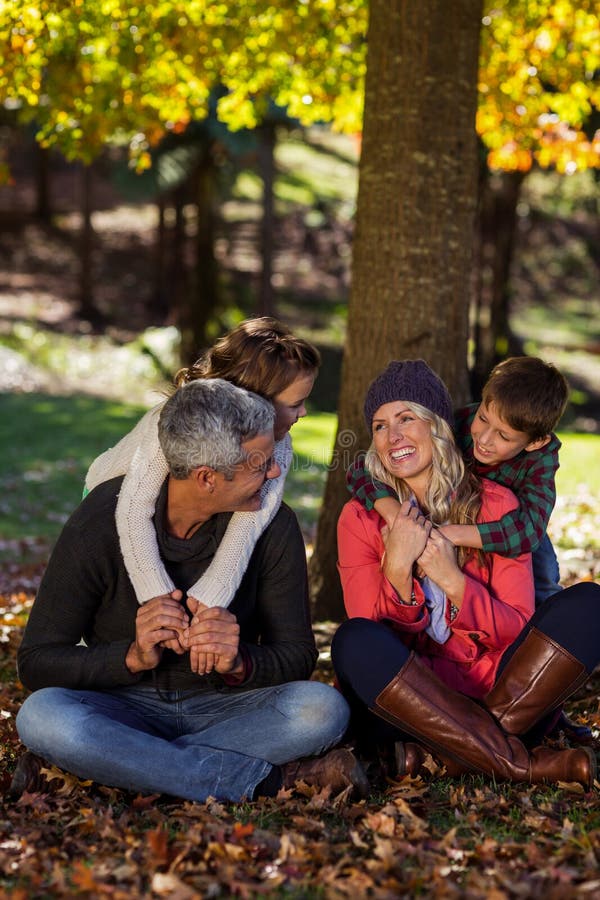 Happy Family Sitting Under Tree at Park Stock Image - Image of ...