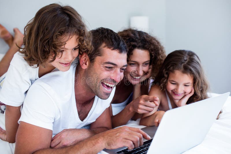 Happy Family Using Laptop Together on Bed Stock Image - Image of four ...