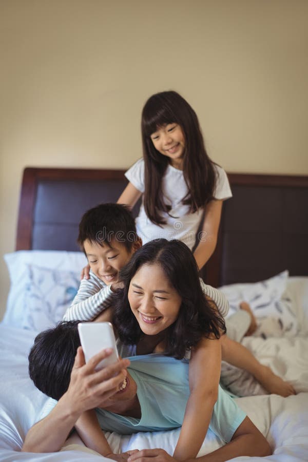 Happy Family Using Mobile Phone in the Bed Room Stock Image - Image of ...