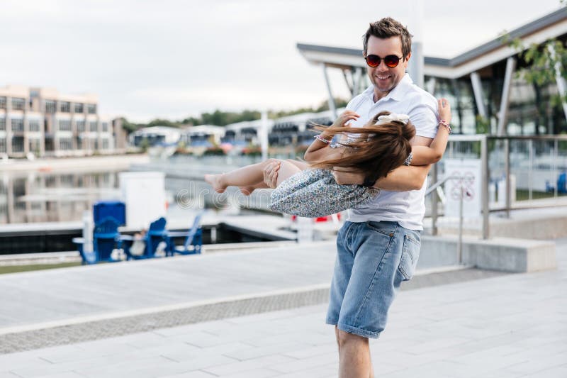 A Happy Father Holds His Daughter in His Arms and Spins Her Around ... A Happy Father Holds His Daughter in His Arms and Spins Her Around ...