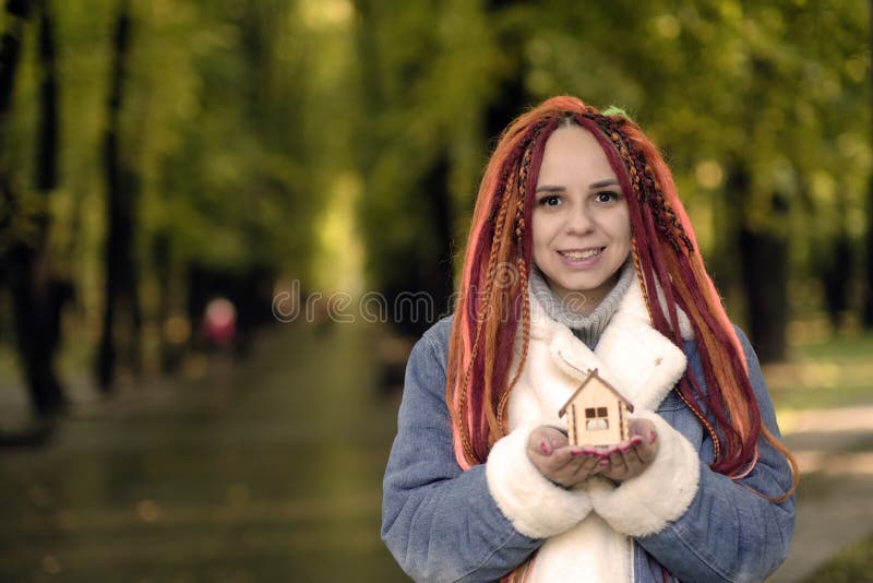 Happy Female Holding Model Home in Park. Positive Young Woman with ... Happy Female Holding Model Home in Park. Positive Young Woman with ...