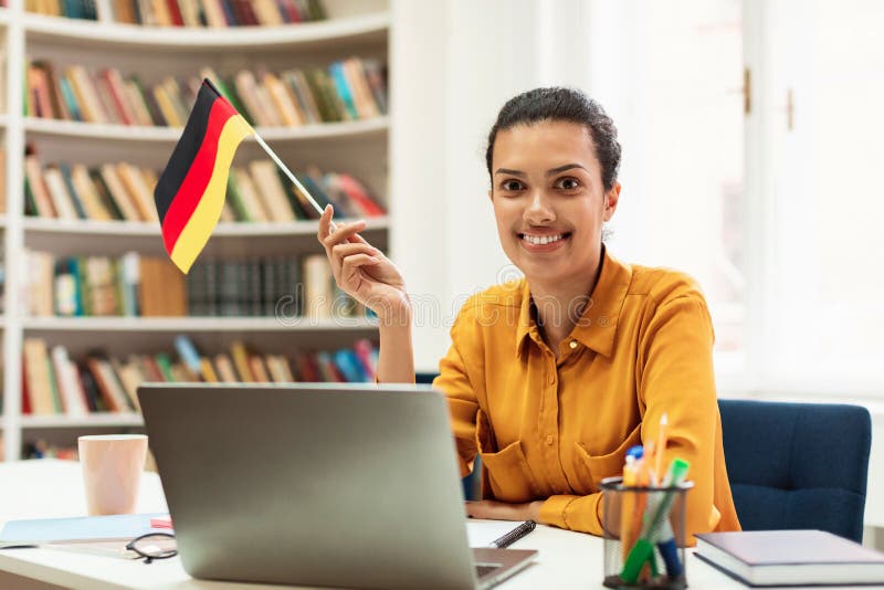 Happy Female Tutor Sitting at Table with Flag of Germany, Using Laptop ...