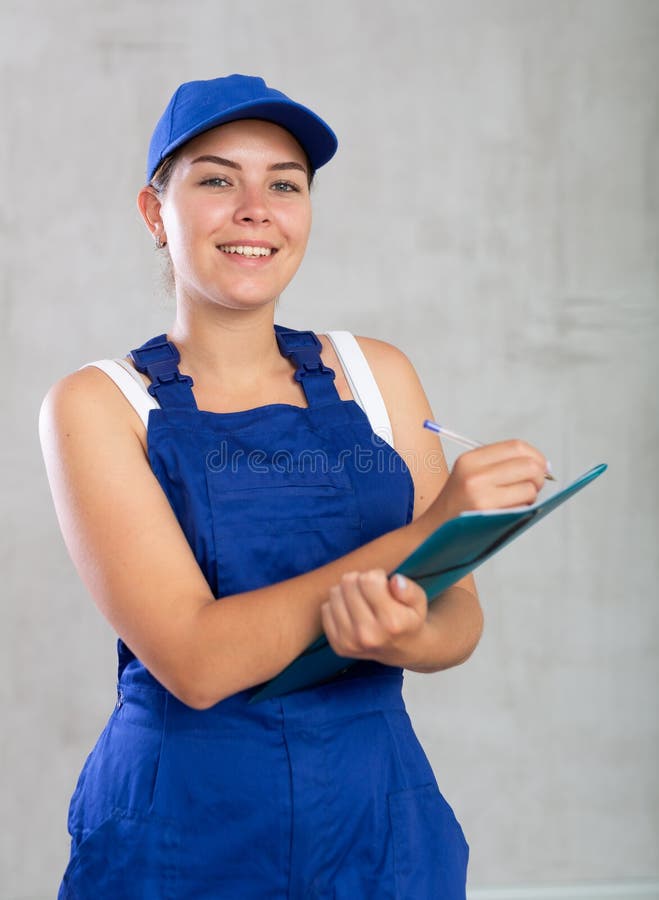 Happy Female Worker in Work Clothes Making Notes in File with Papers ...