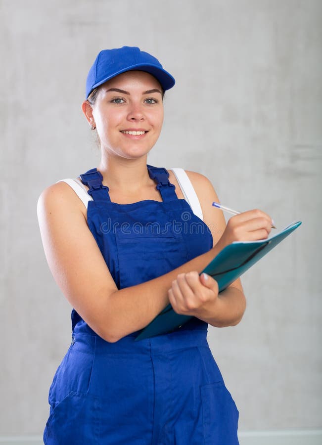 Happy Female Worker in Work Clothes Making Notes in File with Papers ...