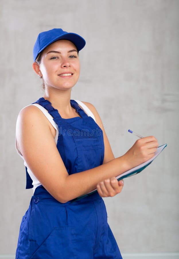 Happy Female Worker in Work Clothes Making Notes in File with Papers ...