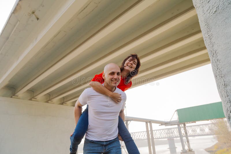 Happy Girl on the Back of a Man at the Bridge. Lovers Have Fun. Stock ...