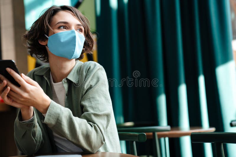 Happy Girl in Protective Mask Using Cellphone while Sitting at Cafe ...