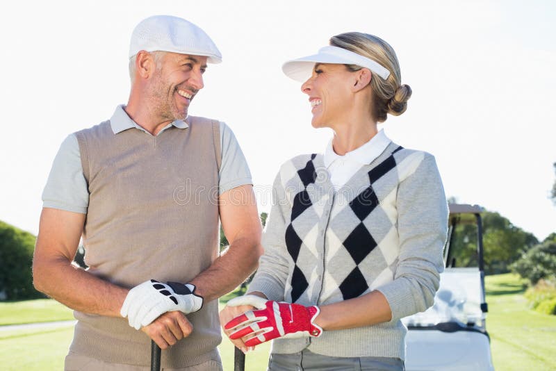 Happy Golfing Couple Facing Each Other with Golf Buggy Behind Stock ...