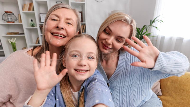 Happy Grandmother Mother And Granddaughter Are Sitting On The Sofa In