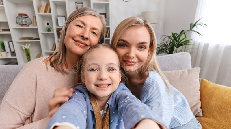 Happy Grandmother Mother And Granddaughter Are Sitting On The Sofa In