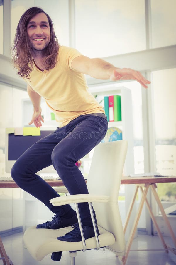 Happy Hipster Standing on Chair by Desk in Office Stock Photo - Image ...