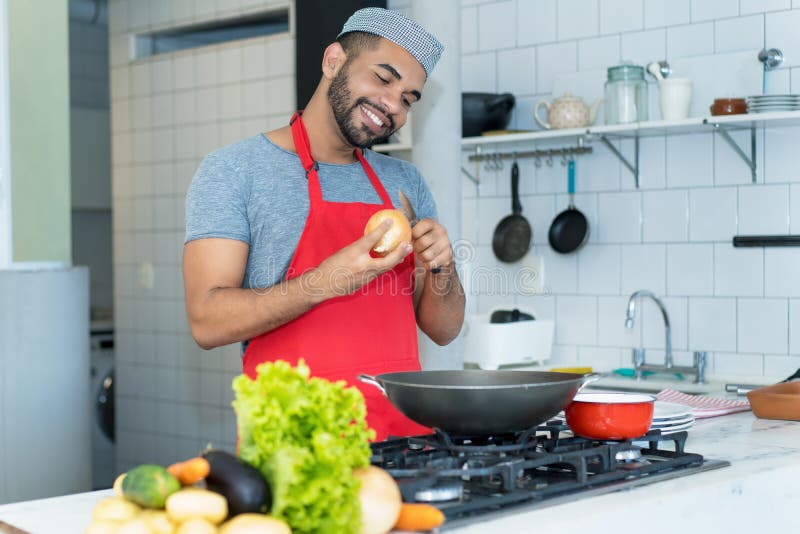 Happy Hispanic Cook with Red Apron Preparing Food at Kitchen Stock ...