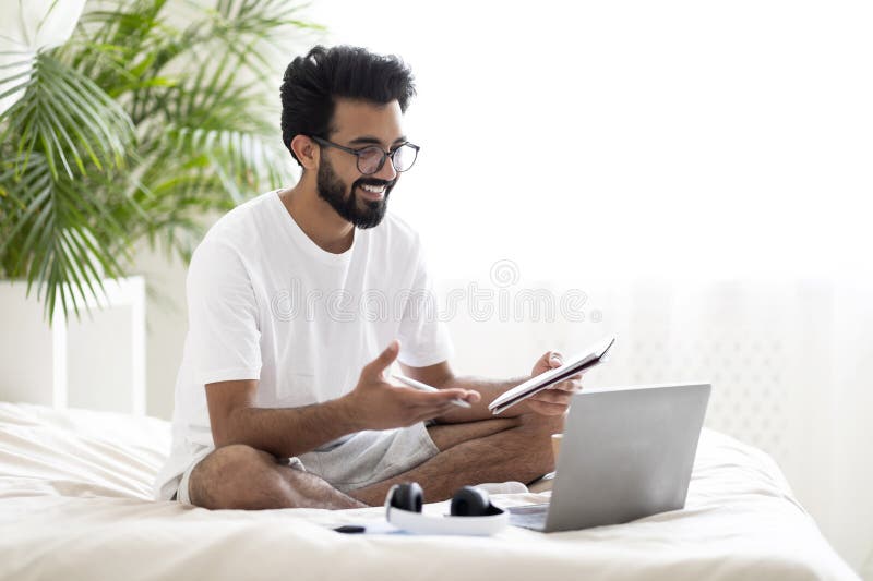 Happy Indian Man Making Video Call with Laptop while Sitting in Bed ...