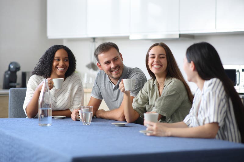 Happy Interracial Friends Talking in the Kitchen and Drinking Stock ...