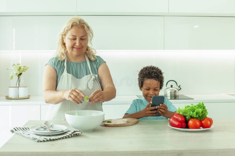 Happy Kid Boy Using Phone while Cooking in Kitchen with Her Mother ...