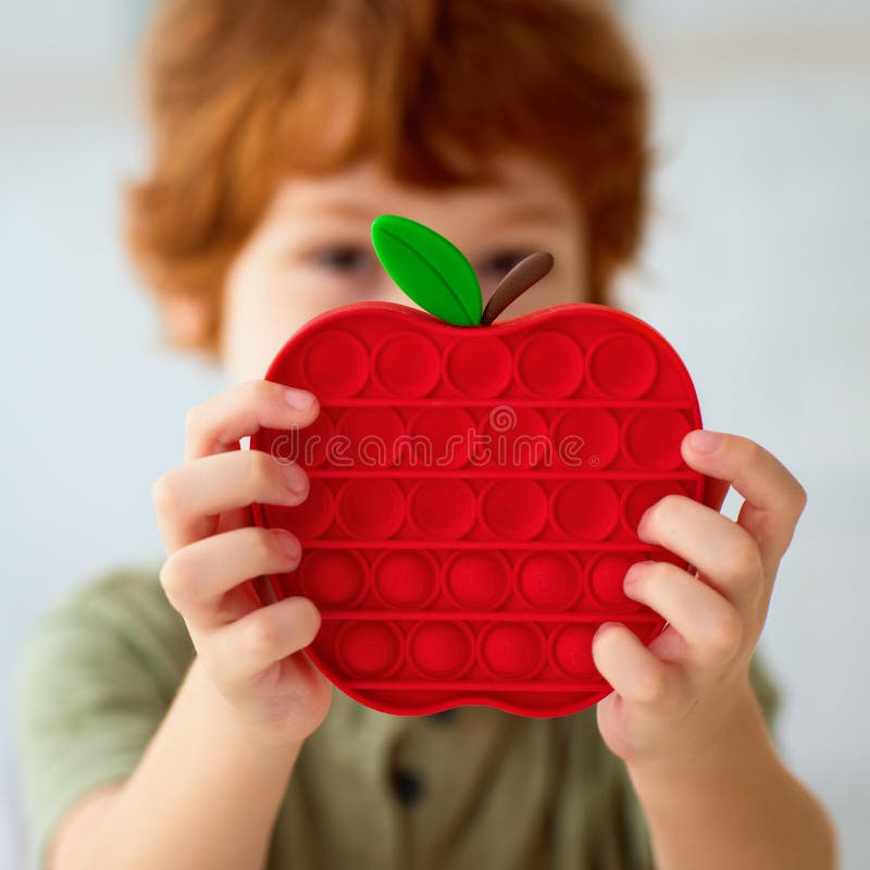 Happy Kid Holding a Vibrant Sensory Toy, Pop it Fidget Toy in Apple ...